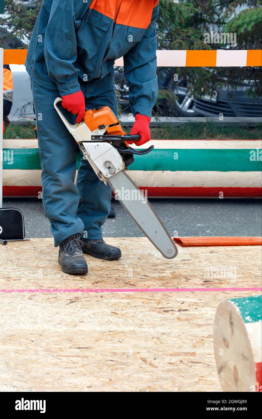 An employee checks and adjusts the chainsaw against the backdrop of the ...