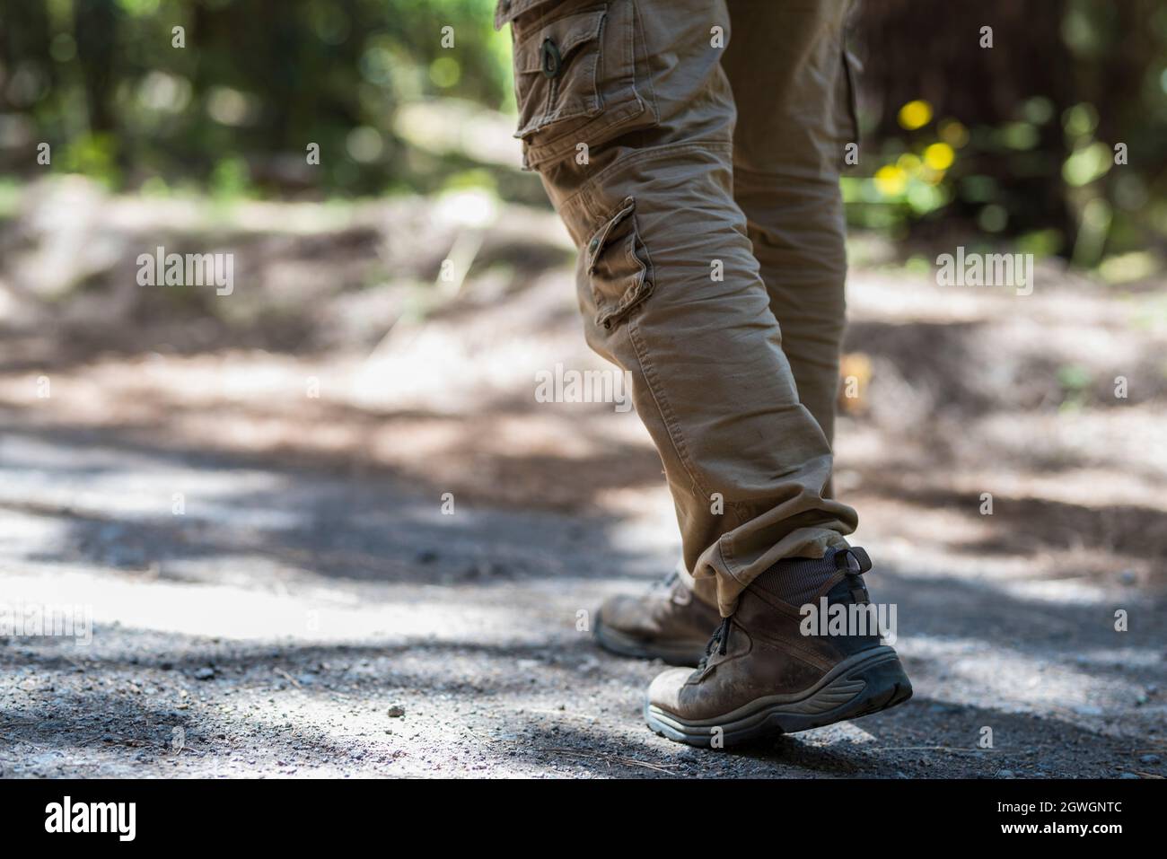 Man feet wearing hiking shoes walking through the forest path in summer ...