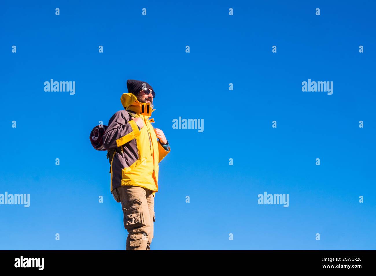 Mature man in backpack and sunglasses against blue sky. Male hiker in ...