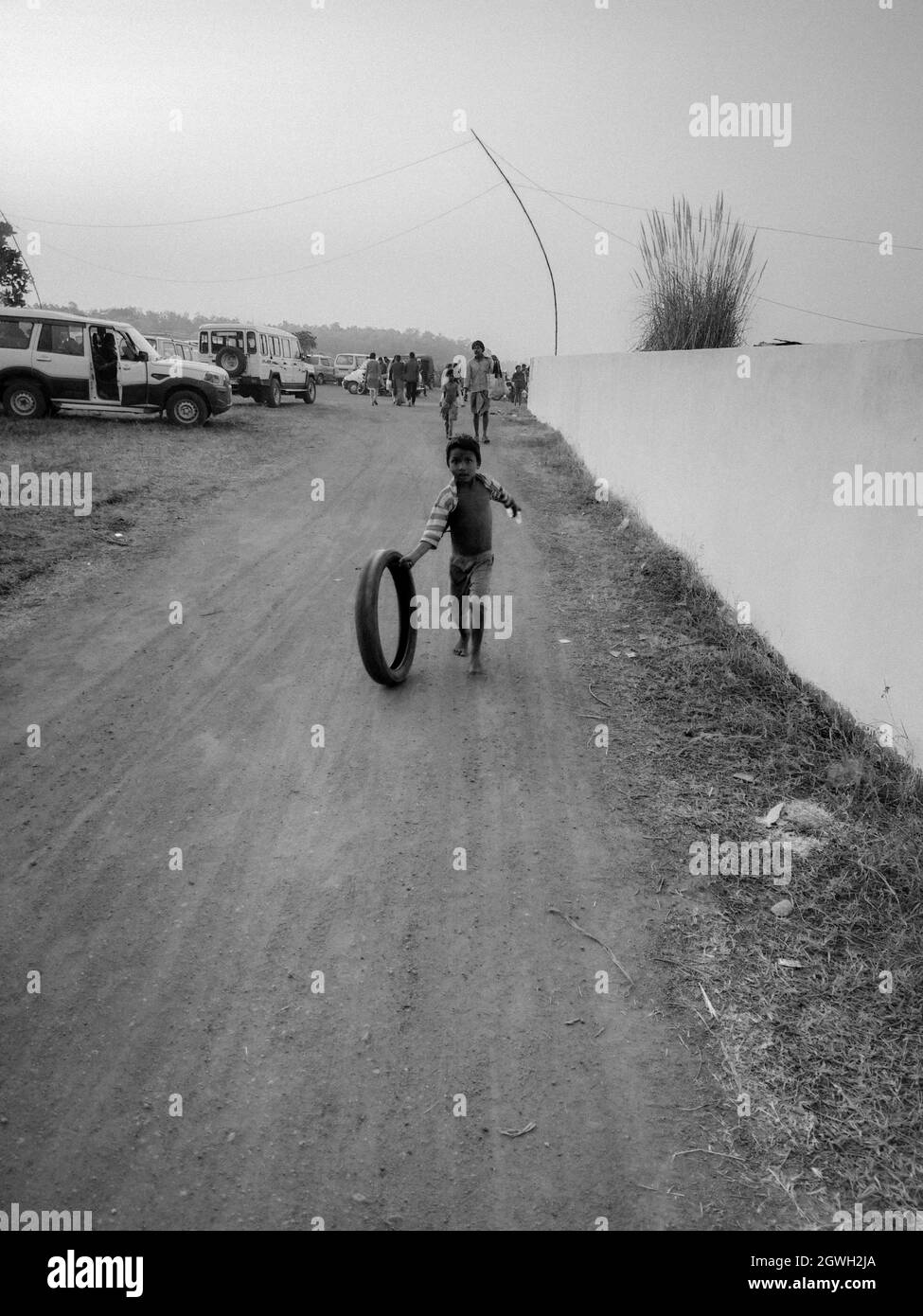 Boy Playing With Wheel On Road Stock Photo - Alamy