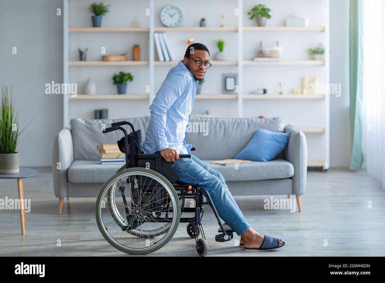 Paraplegic young black man trying to get up from wheelchair at home ...