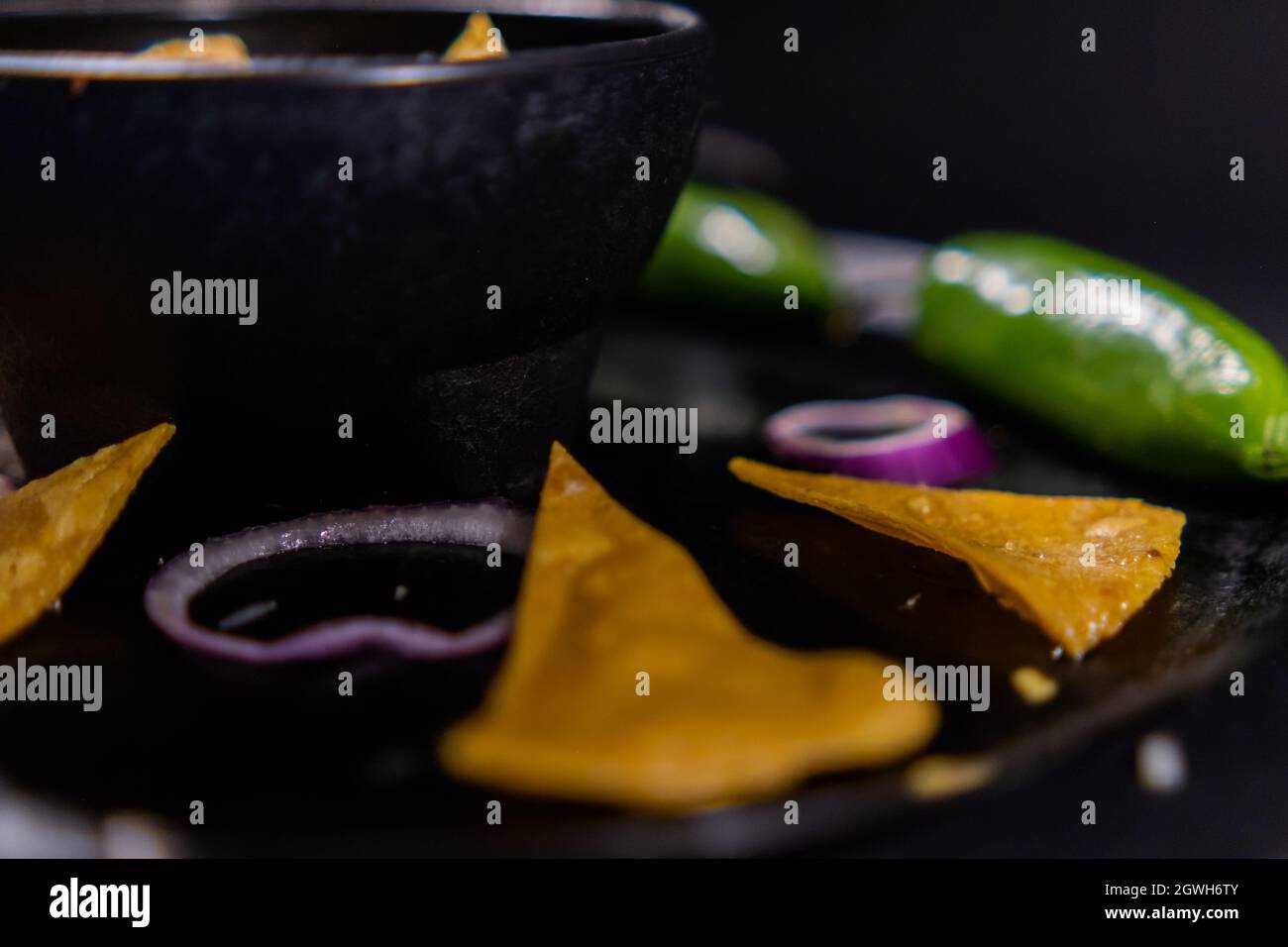 Tortilla chips, chili peppers, and onion slices on Mexican comal Stock ...