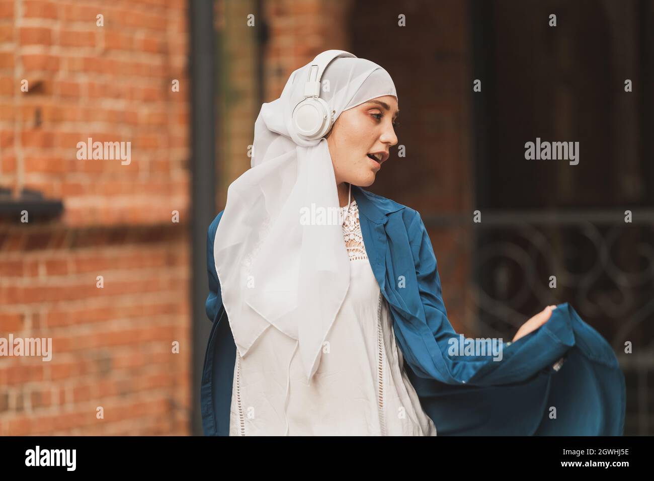 Portrait of young arabian muslim woman listening music with headphone ...