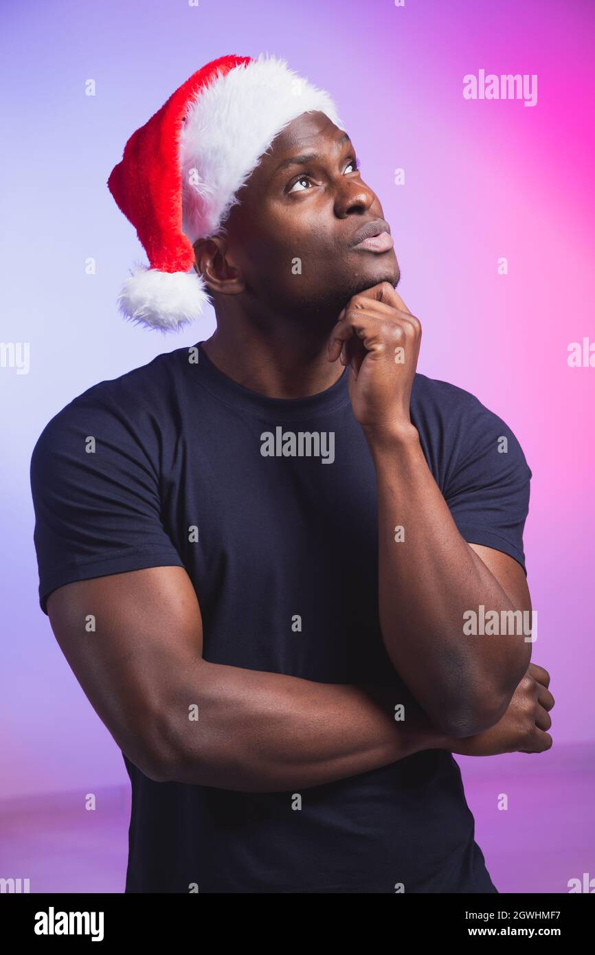 Portrait of pensive african american man in santa hat and casual t ...