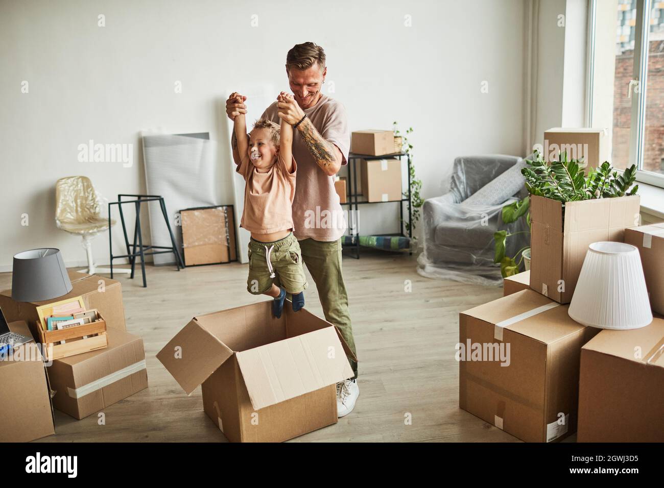 Portrait of happy father playing with son in cardboard boxes while ...