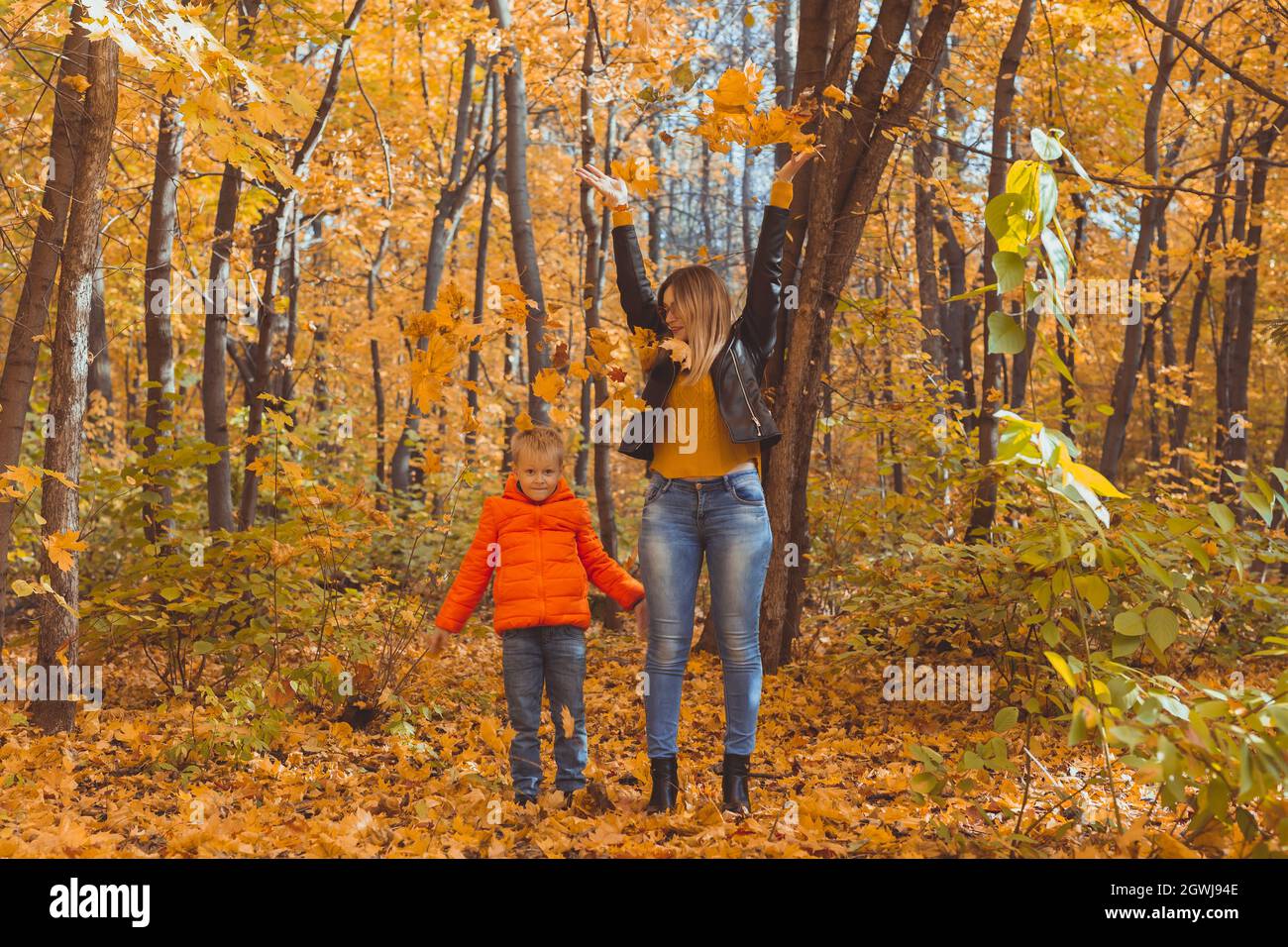 Single parent family playing with autumn leaves in park. Happy mom and ...