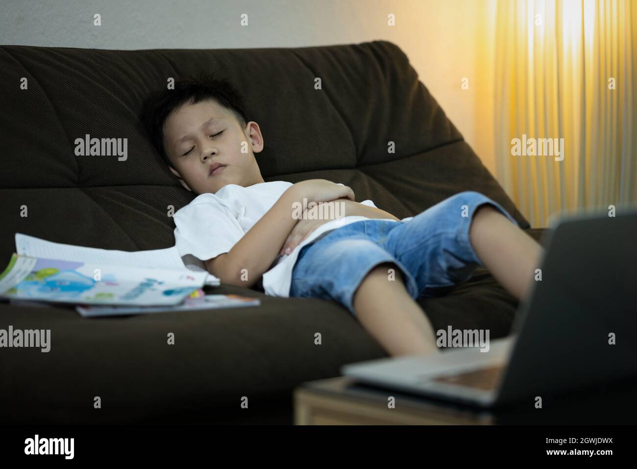 Boy Sleeping On Sofa With Books At Home Stock Photo - Alamy