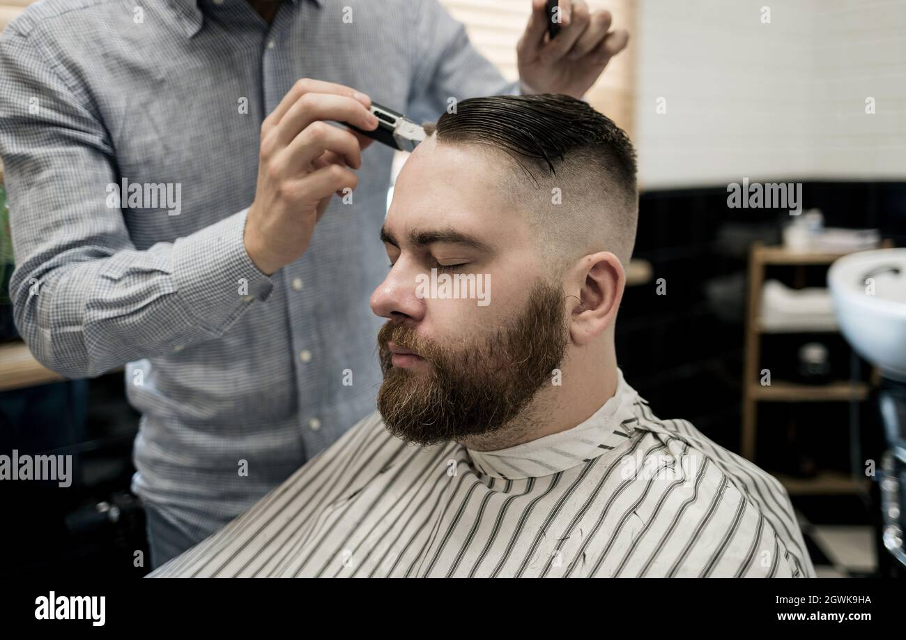 stylish hipster guy in barbershop. barber does a man's haircut in the ...