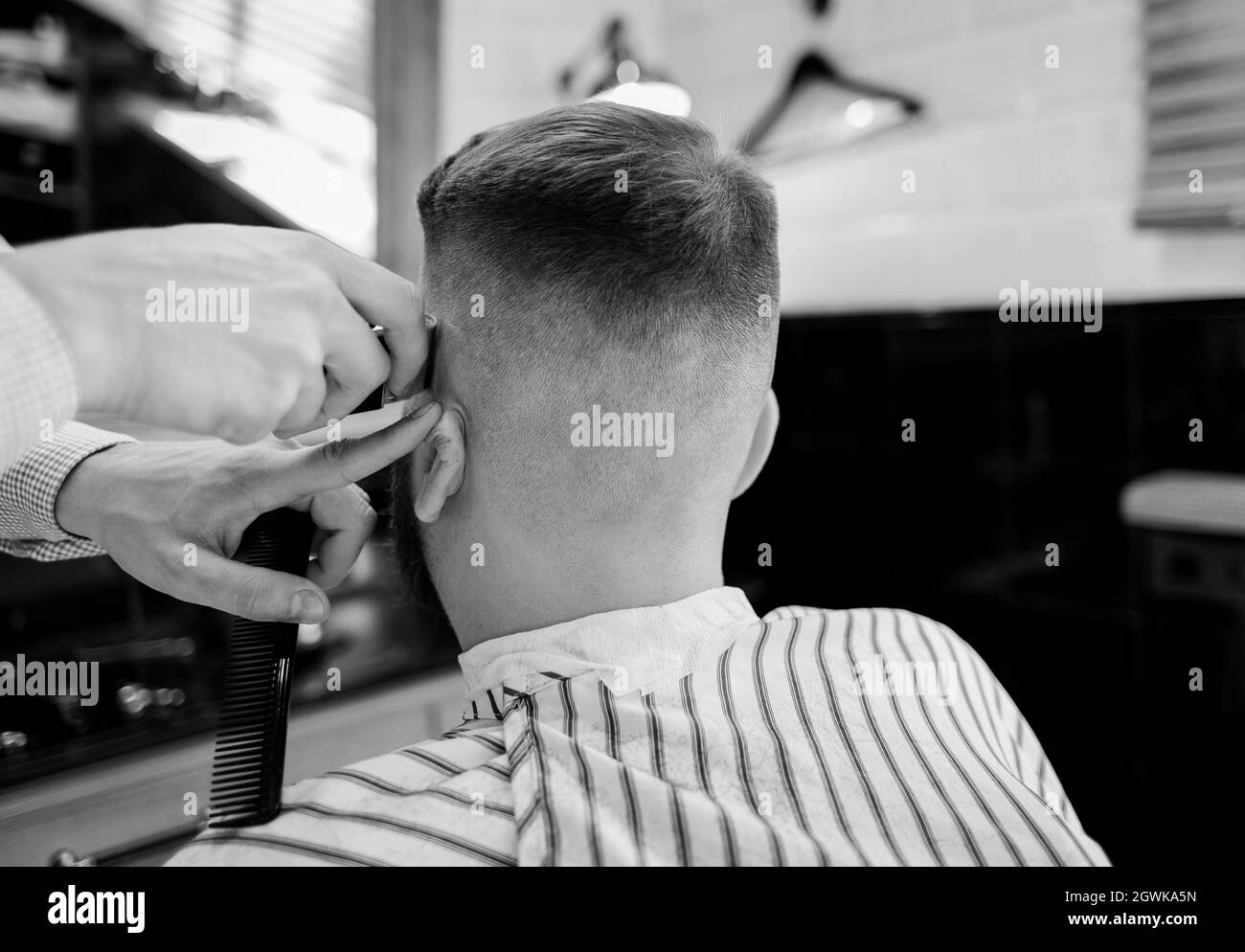 barber making modern haircut of brutal bearded guy in salon. man in ...