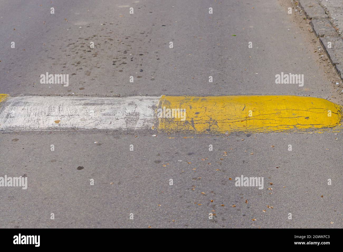Yellow and white concrete speed bump at street Stock Photo - Alamy