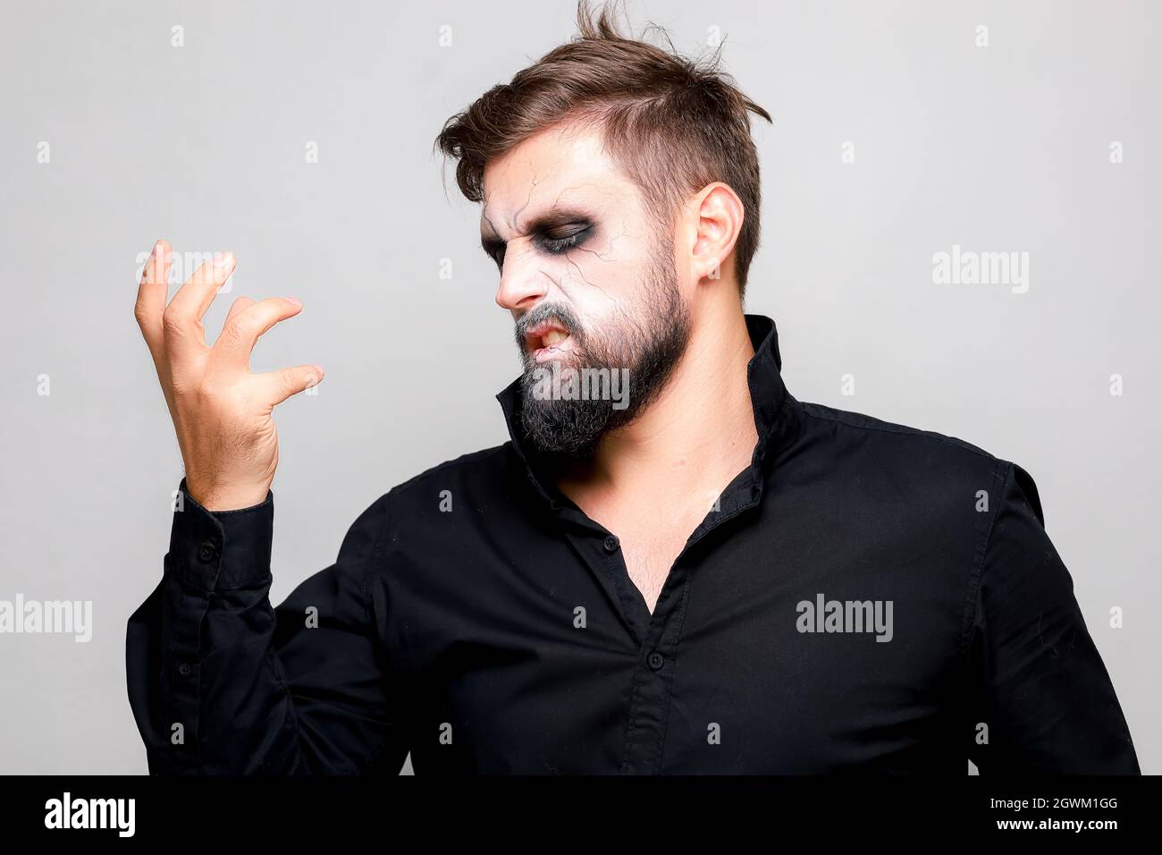 Scary undead-style makeup for Halloween on a bearded man who shows ...