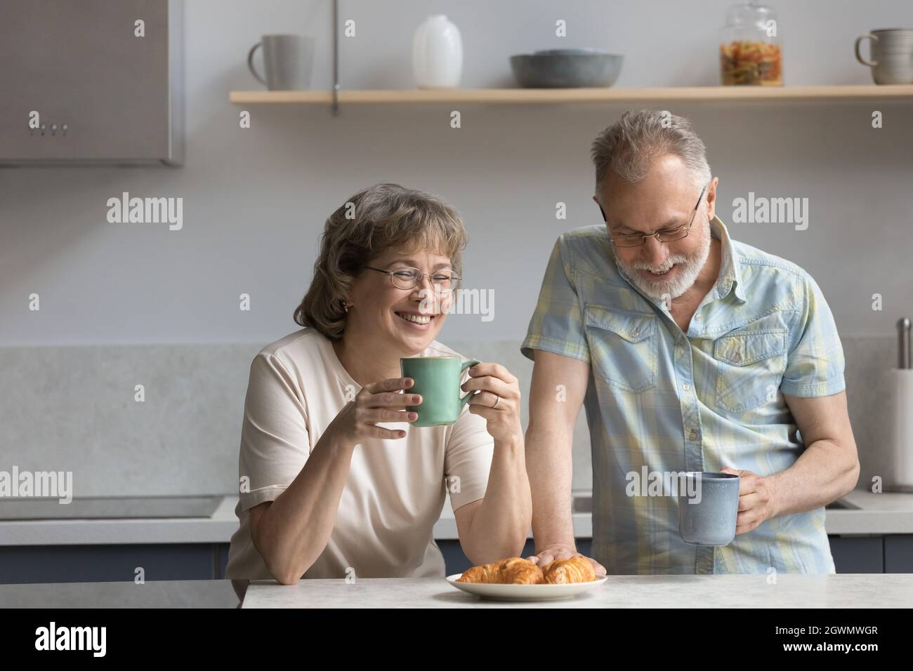 Happy middle aged mature family couple eating breakfast in kitchen ...