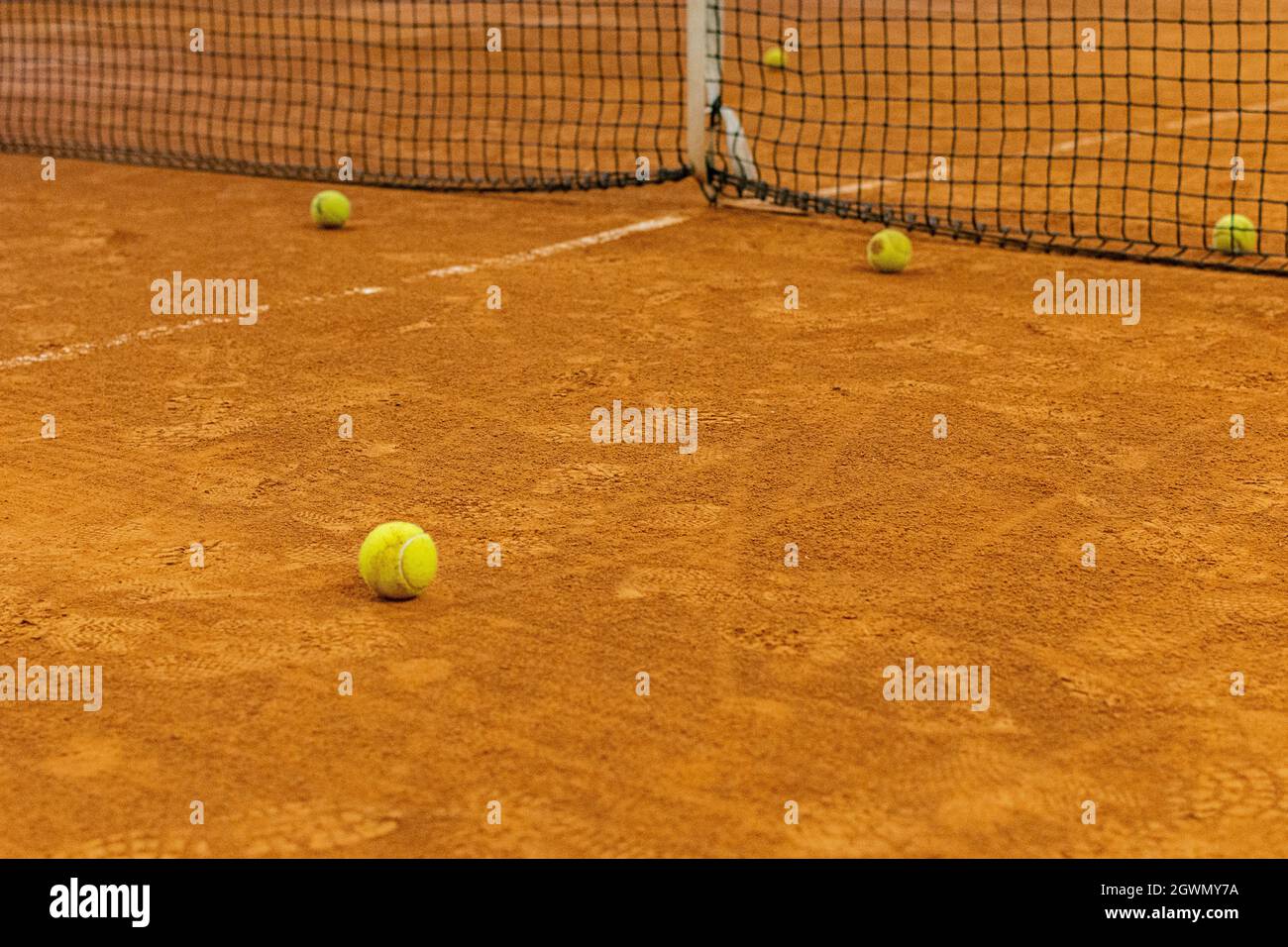 Ground red tennis court with net and balls indoors Stock Photo - Alamy