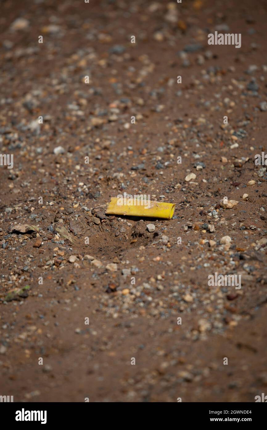 Crushed yellow ammunition shell embedded in the mud Stock Photo - Alamy