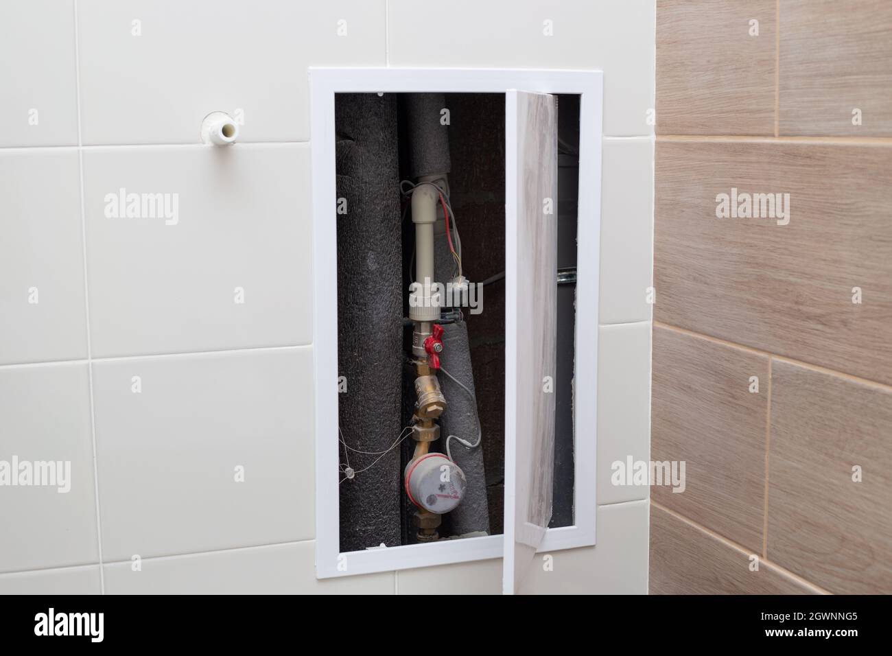 Bathroom wall hatch with pipes and water meter. Transmission of water ...