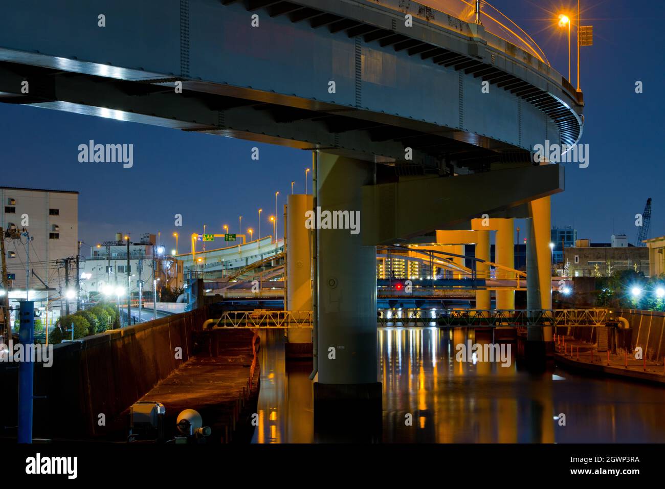 Illuminated Bridge Over River By Buildings In City At Night Stock Photo ...