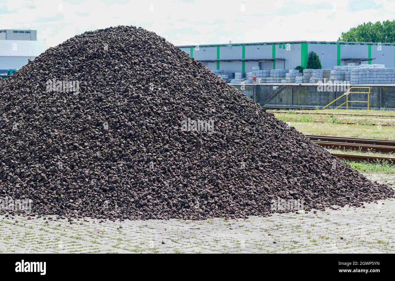 A pile of coal on a concrete ground outdoors at a quarry during daytime ...
