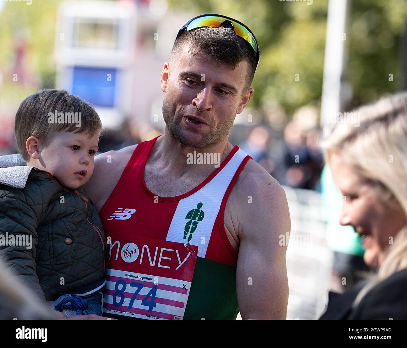 A runner carries a child at the finish line after participating in the ...
