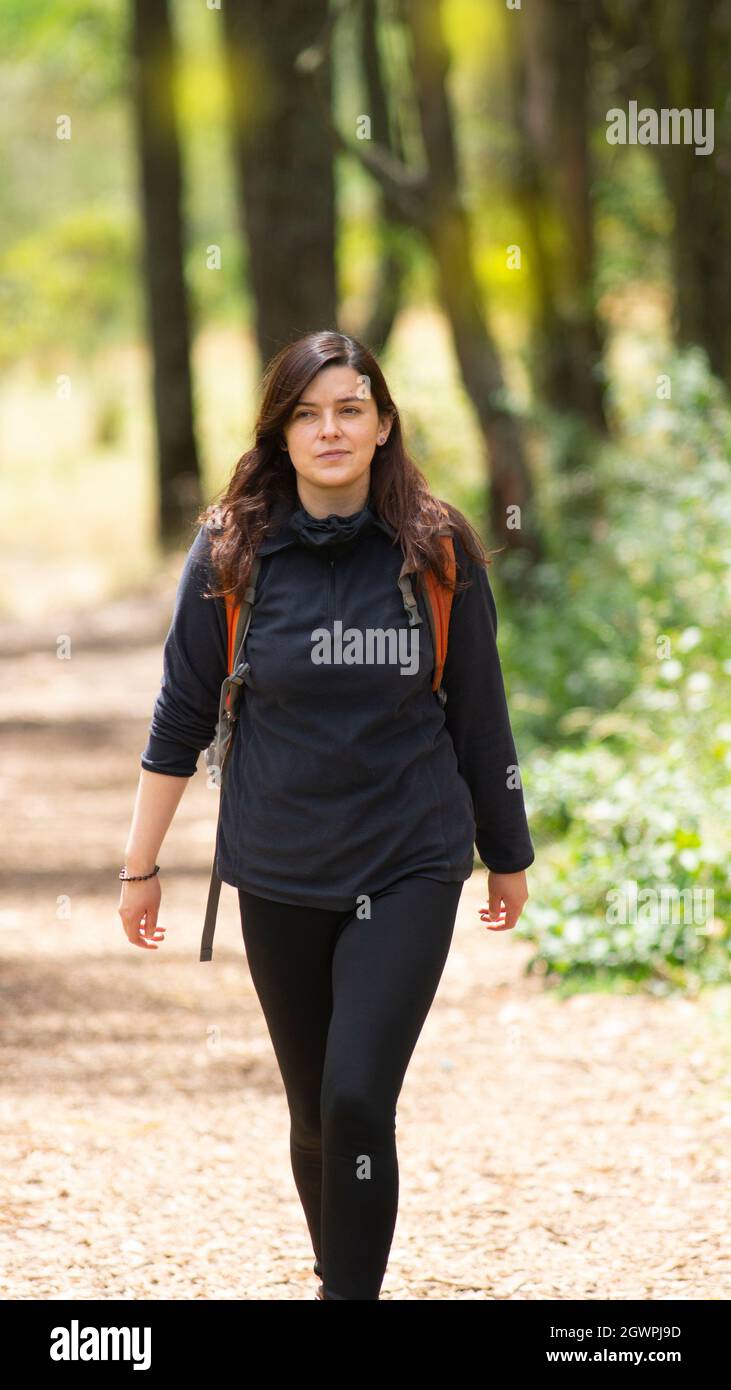 Beautiful Hispanic woman with backpack walking alone on a forest path ...