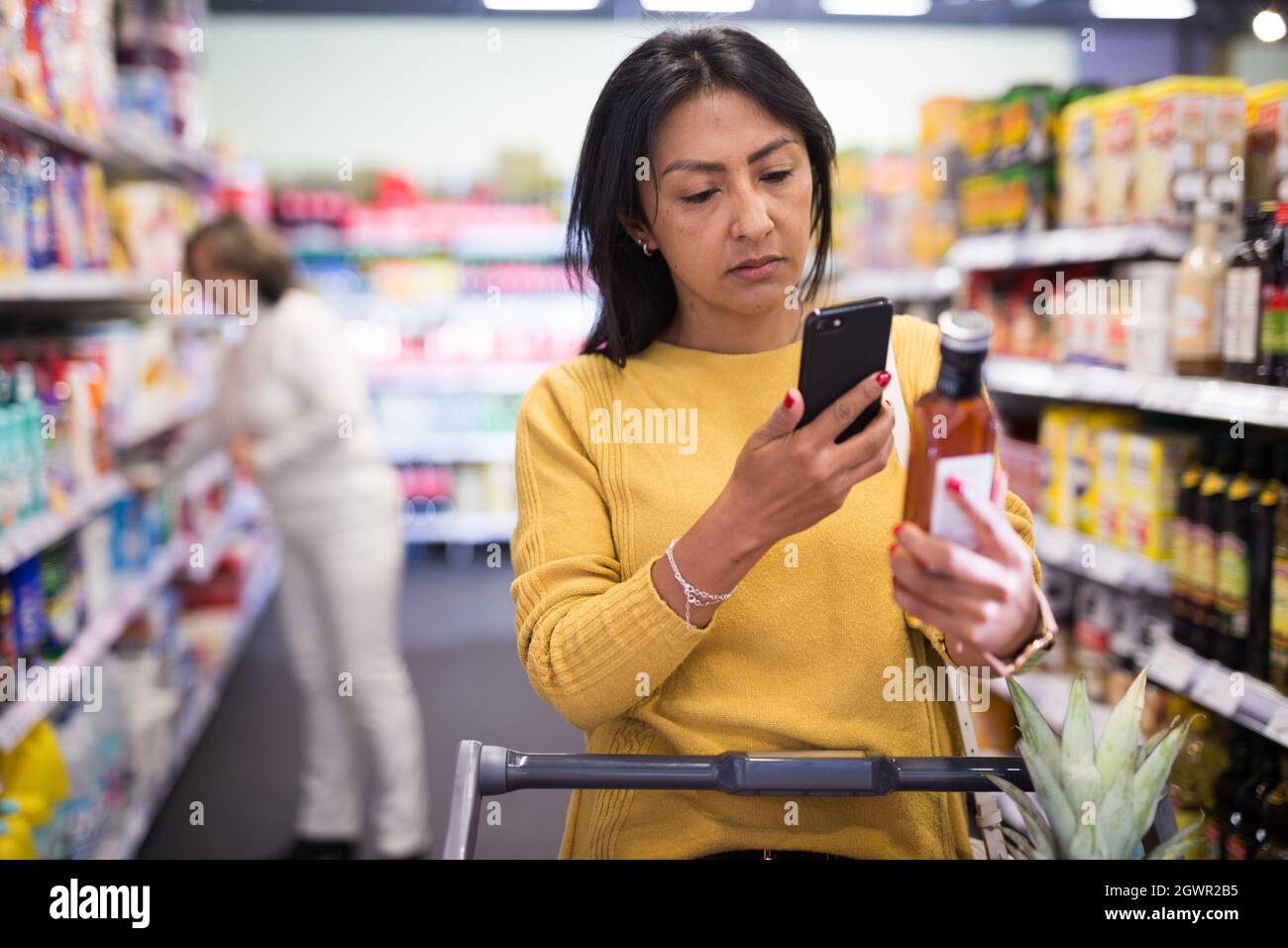Shopper using smartphone scans qr code on label in supermarket Stock ...