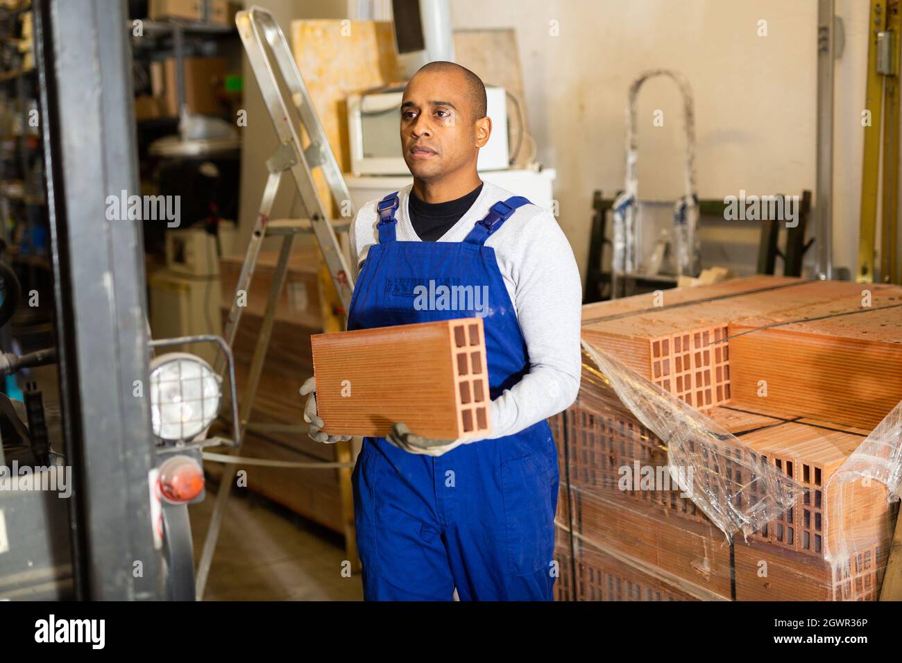 Hispanic worker stacking bricks in warehouse of building materials ...