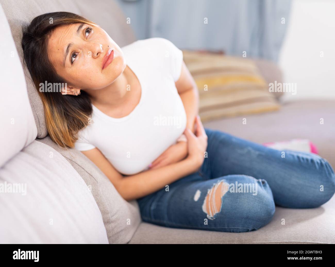 Latino woman experiencing pain in the stomach Stock Photo - Alamy