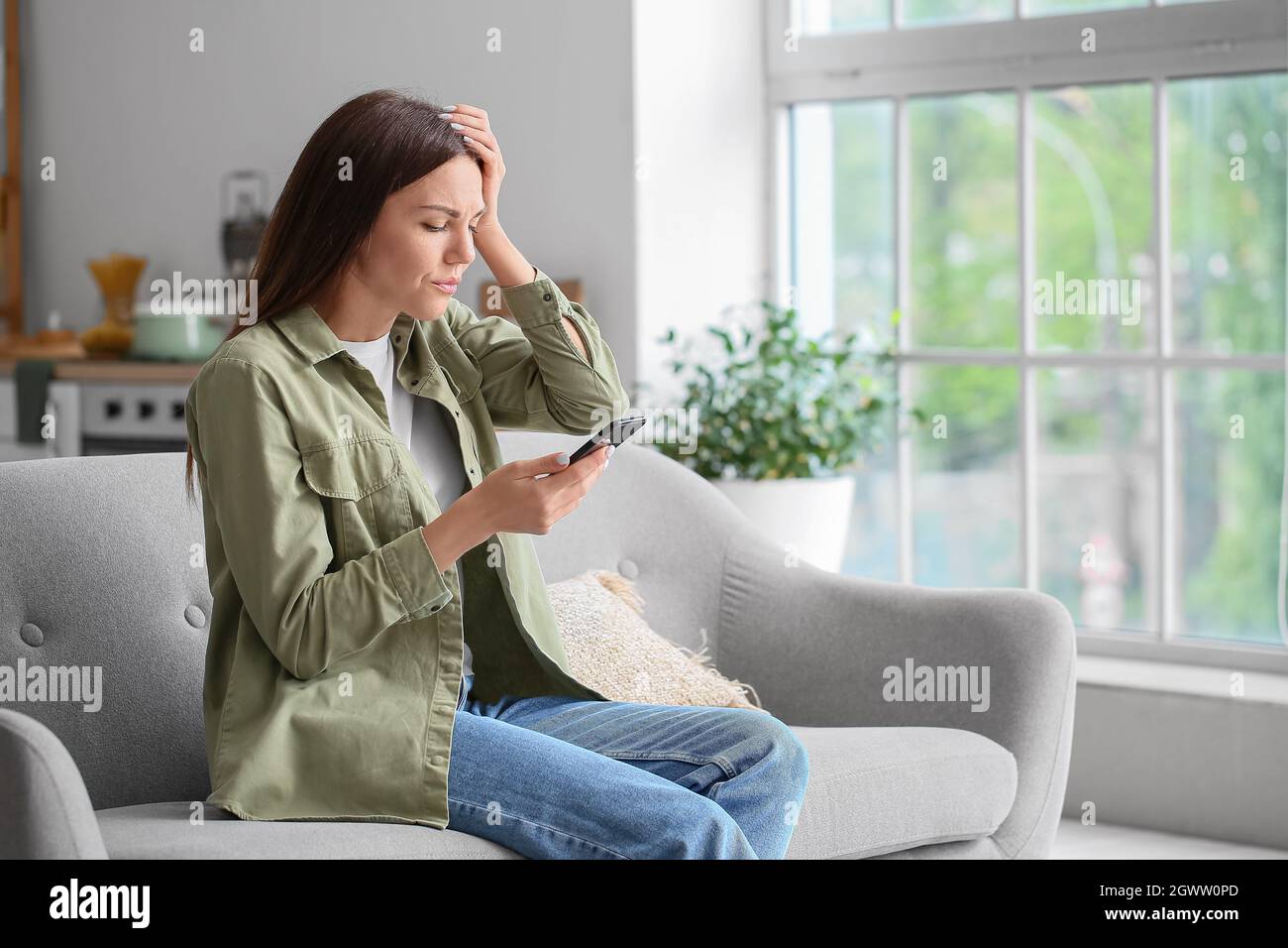 Stressed young woman with phone at home Stock Photo - Alamy