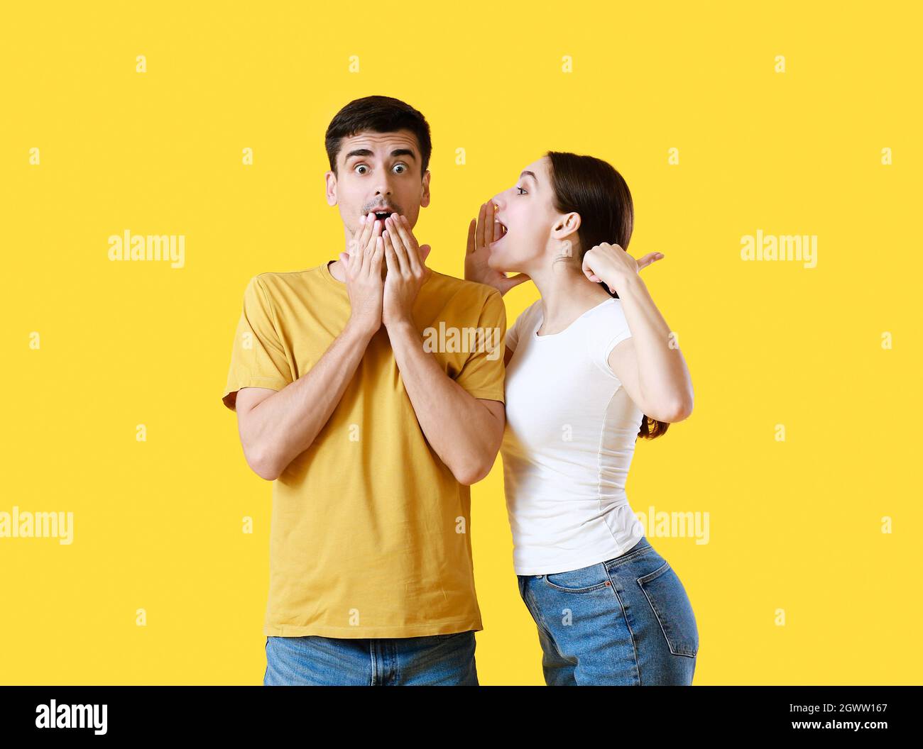 Young woman sharing gossip with her husband on yellow background Stock ...