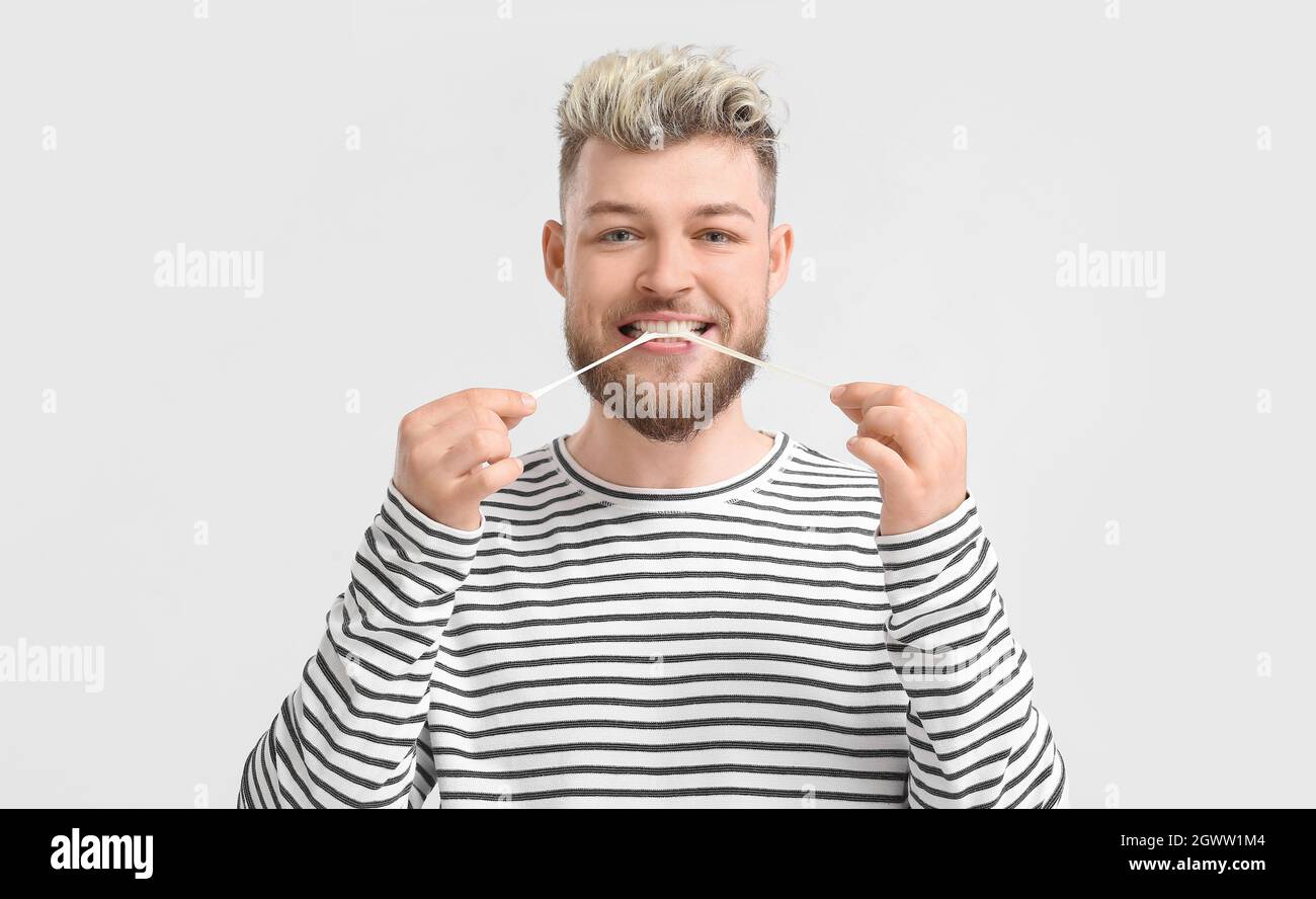 Young man with chewing gum on light background Stock Photo - Alamy