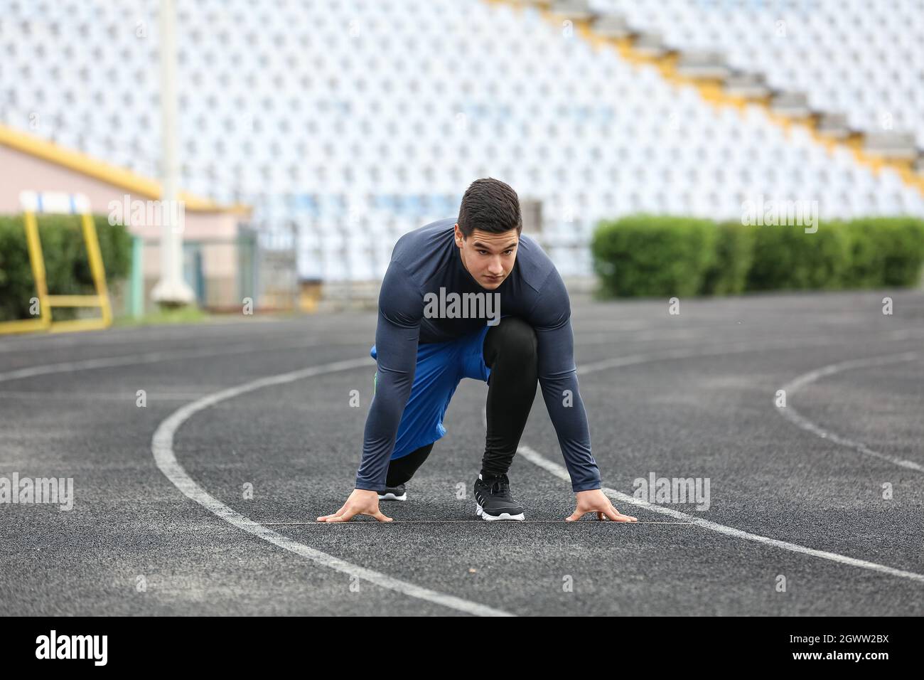 Muscular young man getting ready to run at stadium Stock Photo - Alamy