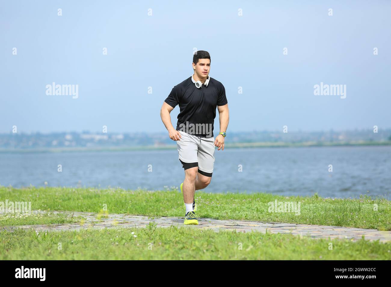 Muscular young man running near river Stock Photo - Alamy