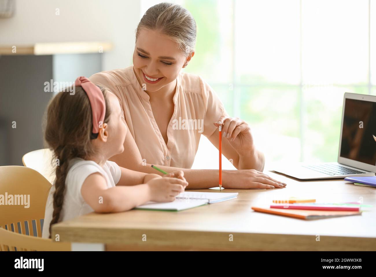 Little girl with her mother doing lessons at home Stock Photo - Alamy