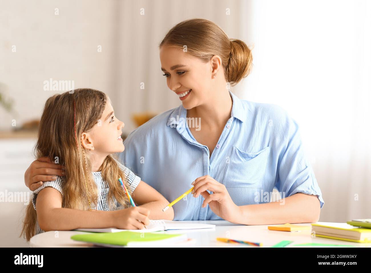 Little girl with her mother doing lessons at home Stock Photo - Alamy