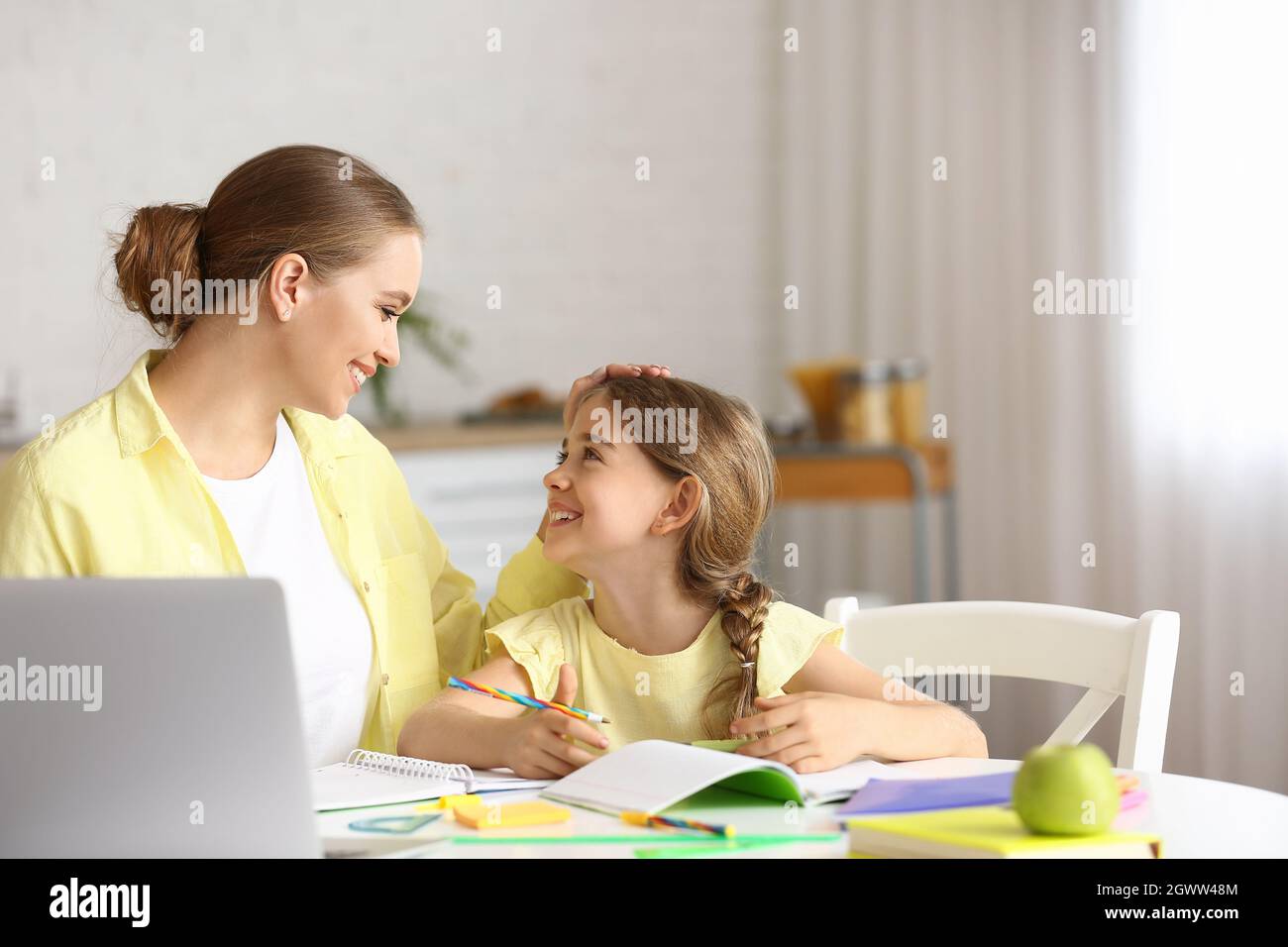 Little girl with her mother doing lessons at home Stock Photo - Alamy