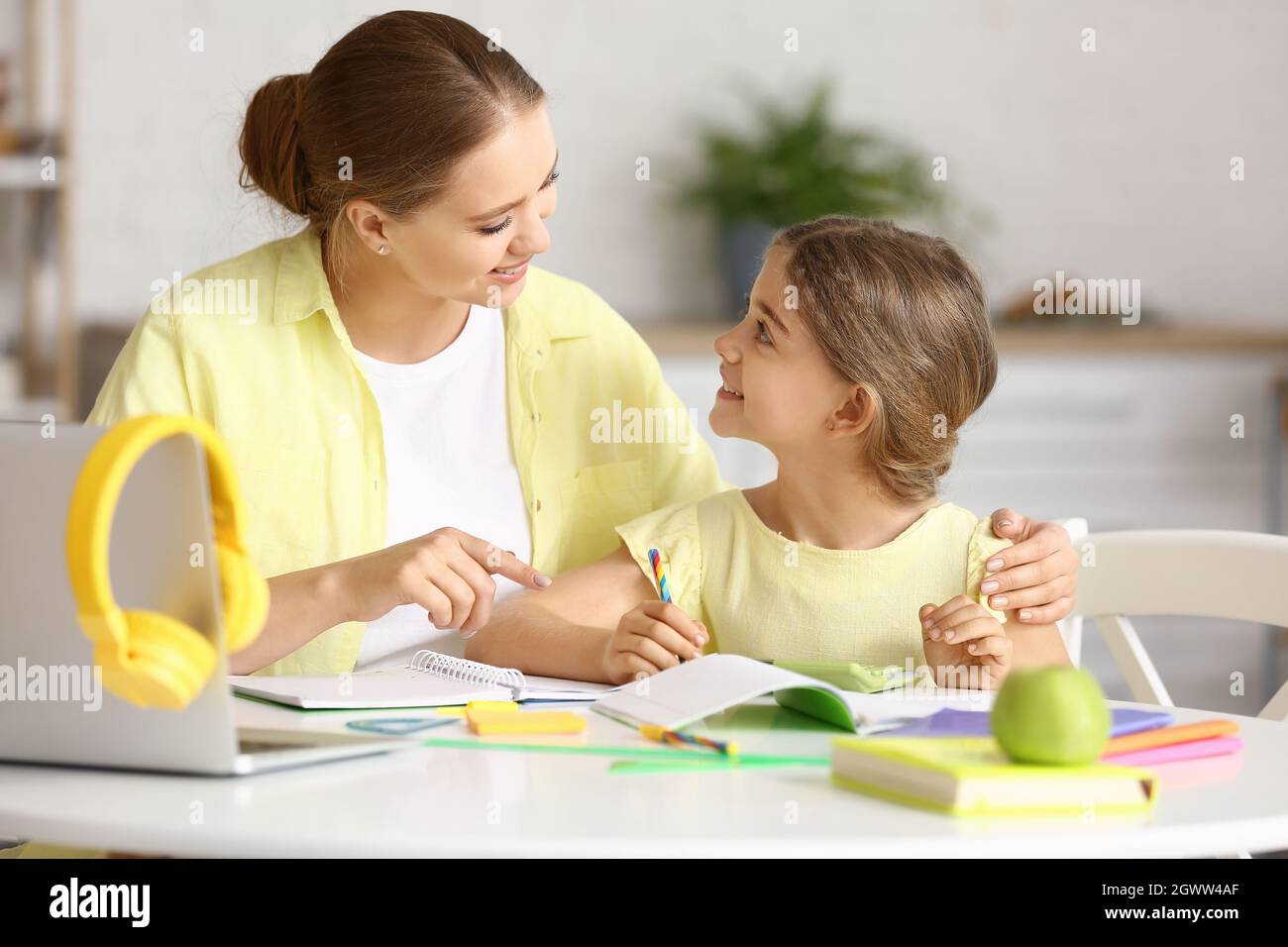 Little girl with her mother doing lessons at home Stock Photo - Alamy