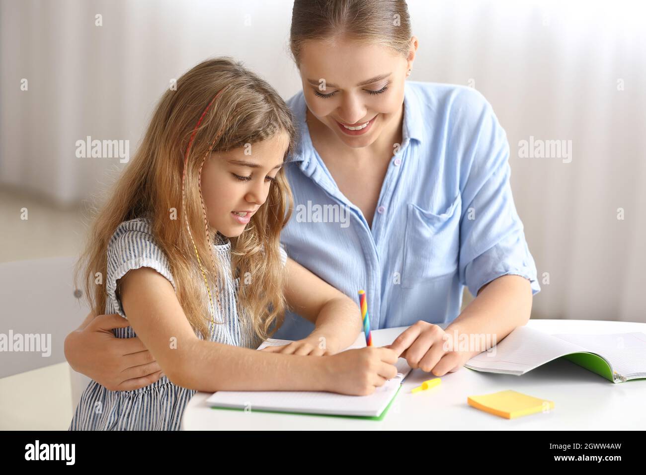 Little girl with her mother doing lessons at home Stock Photo - Alamy