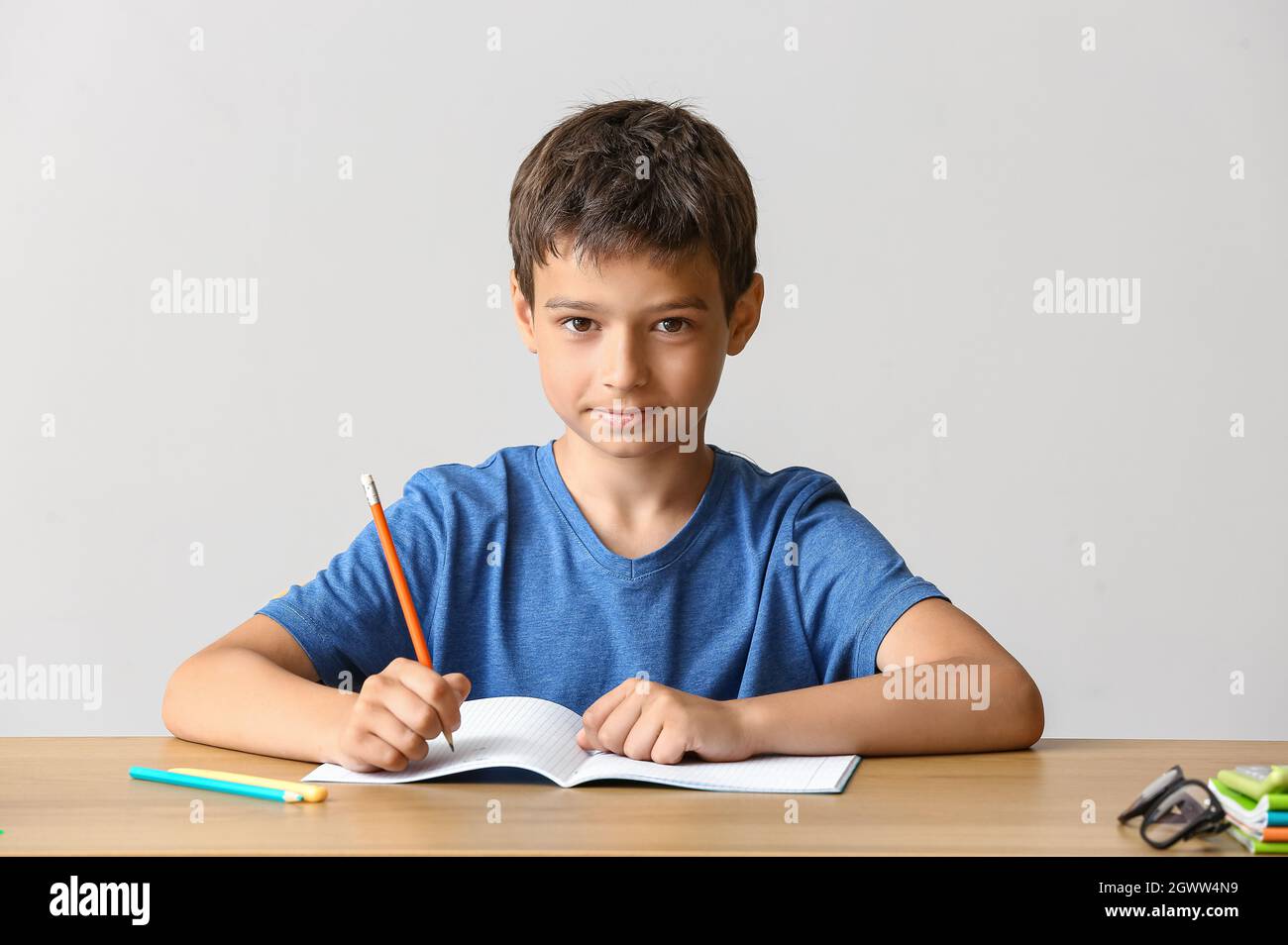 Little boy doing homework at table on light background Stock Photo - Alamy