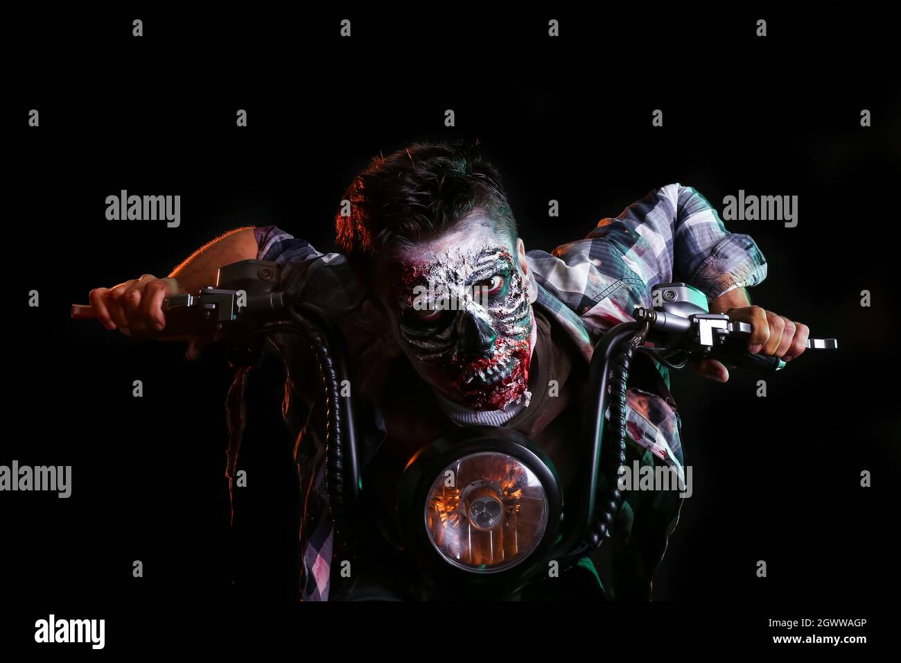 Man dressed for Halloween as zombie with motorcycle on dark background ...