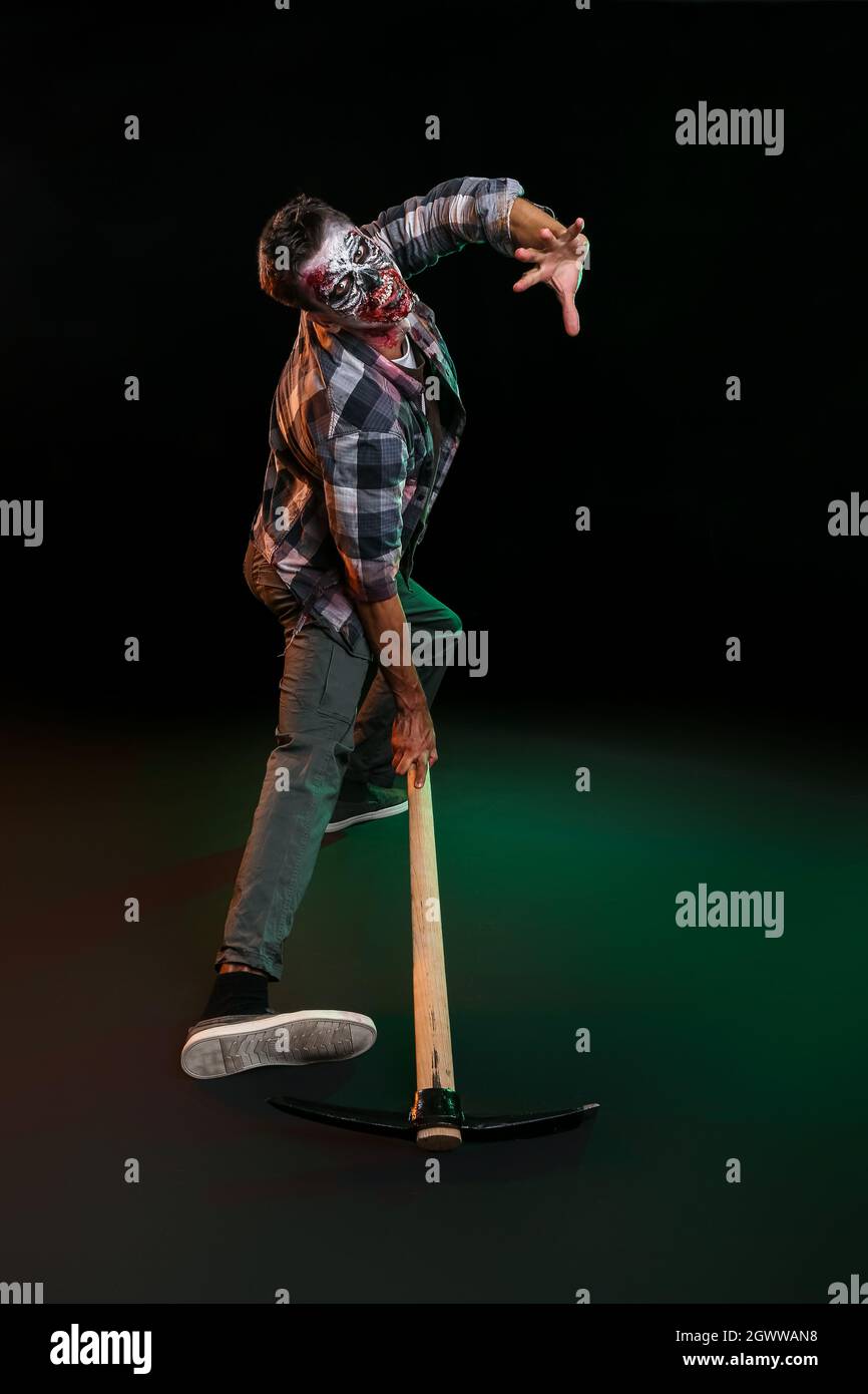 Scary zombie with pick-axe on dark background Stock Photo - Alamy