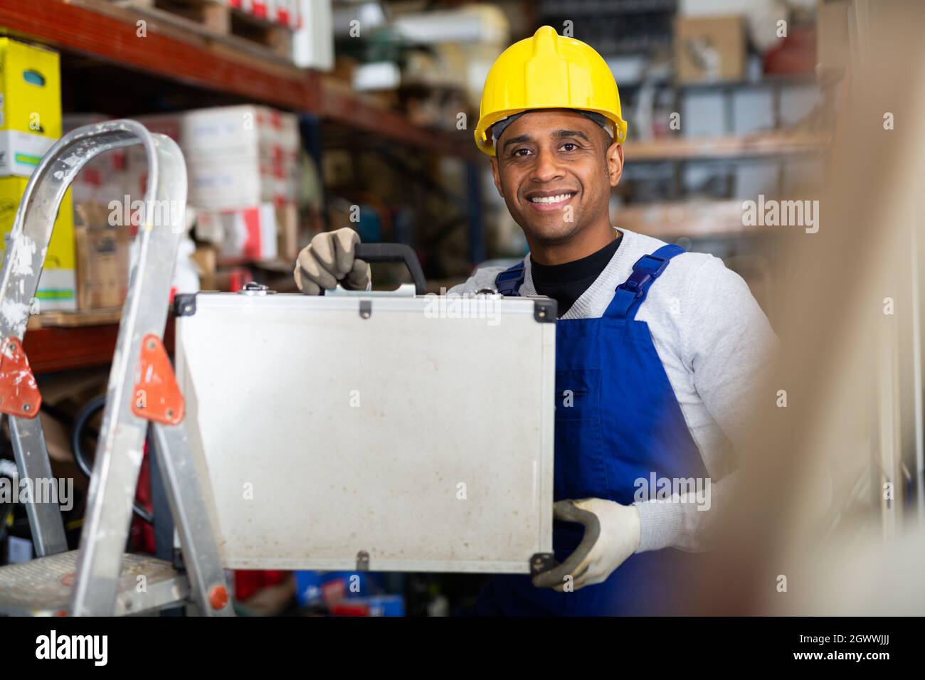 Smiling latin american foreman standing with tool case in store Stock ...