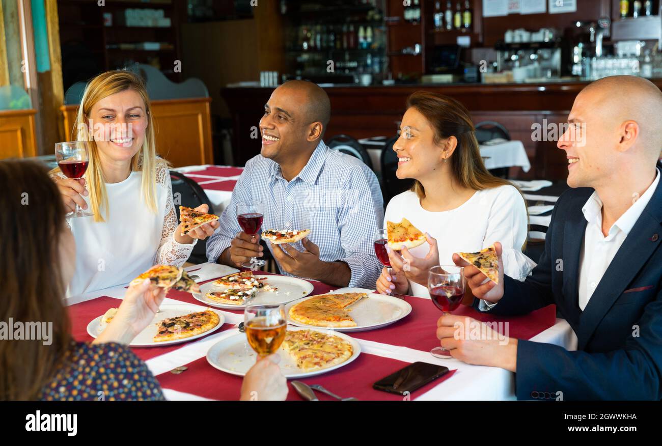 Group of happy people eating pizza with wine in restaurant Stock Photo ...
