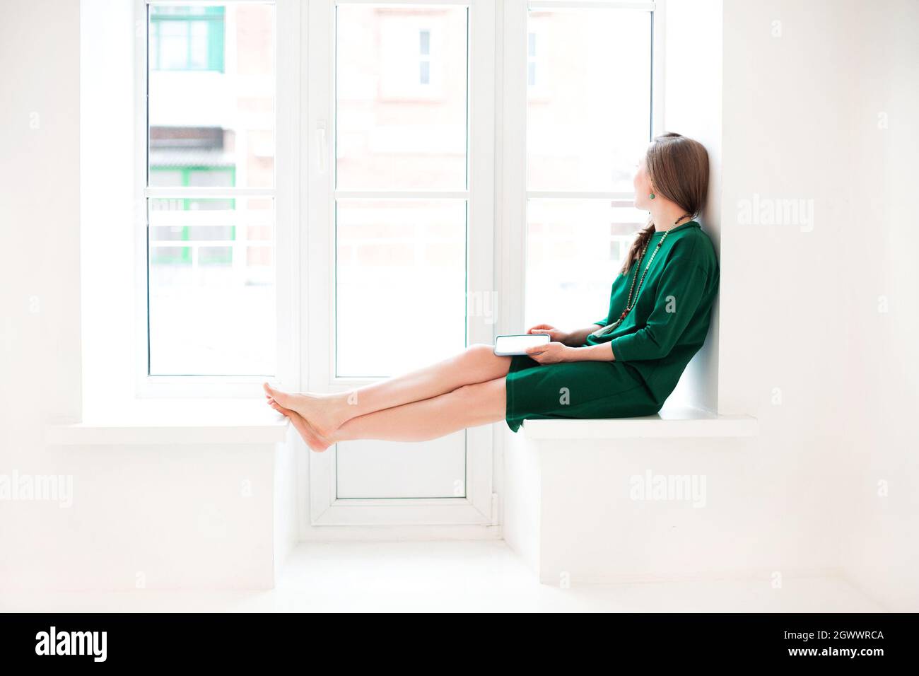 Side View Of Woman Sitting On Window Stock Photo - Alamy