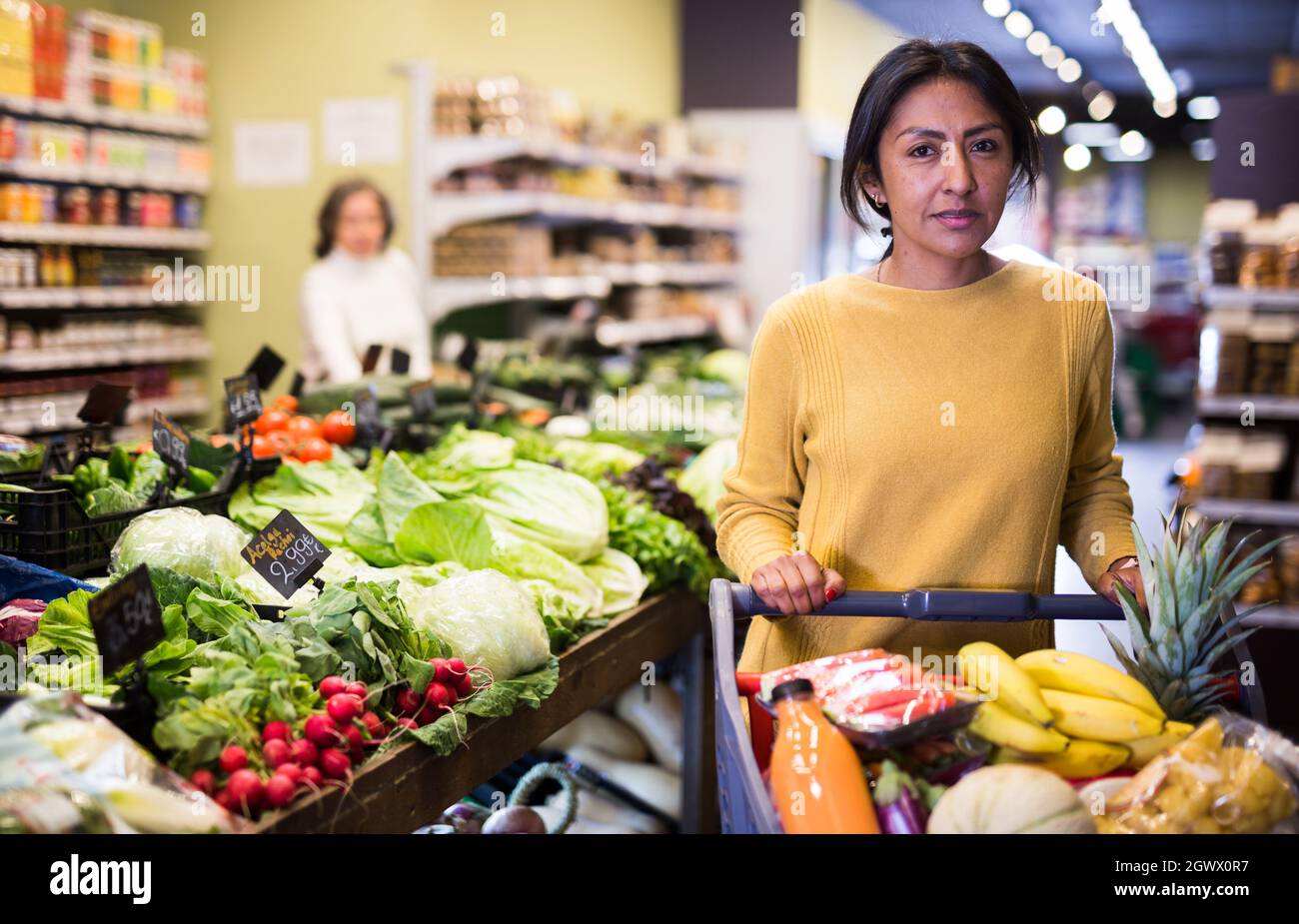 Satisfied hispanic woman with shopping trolley in supermarket Stock ...
