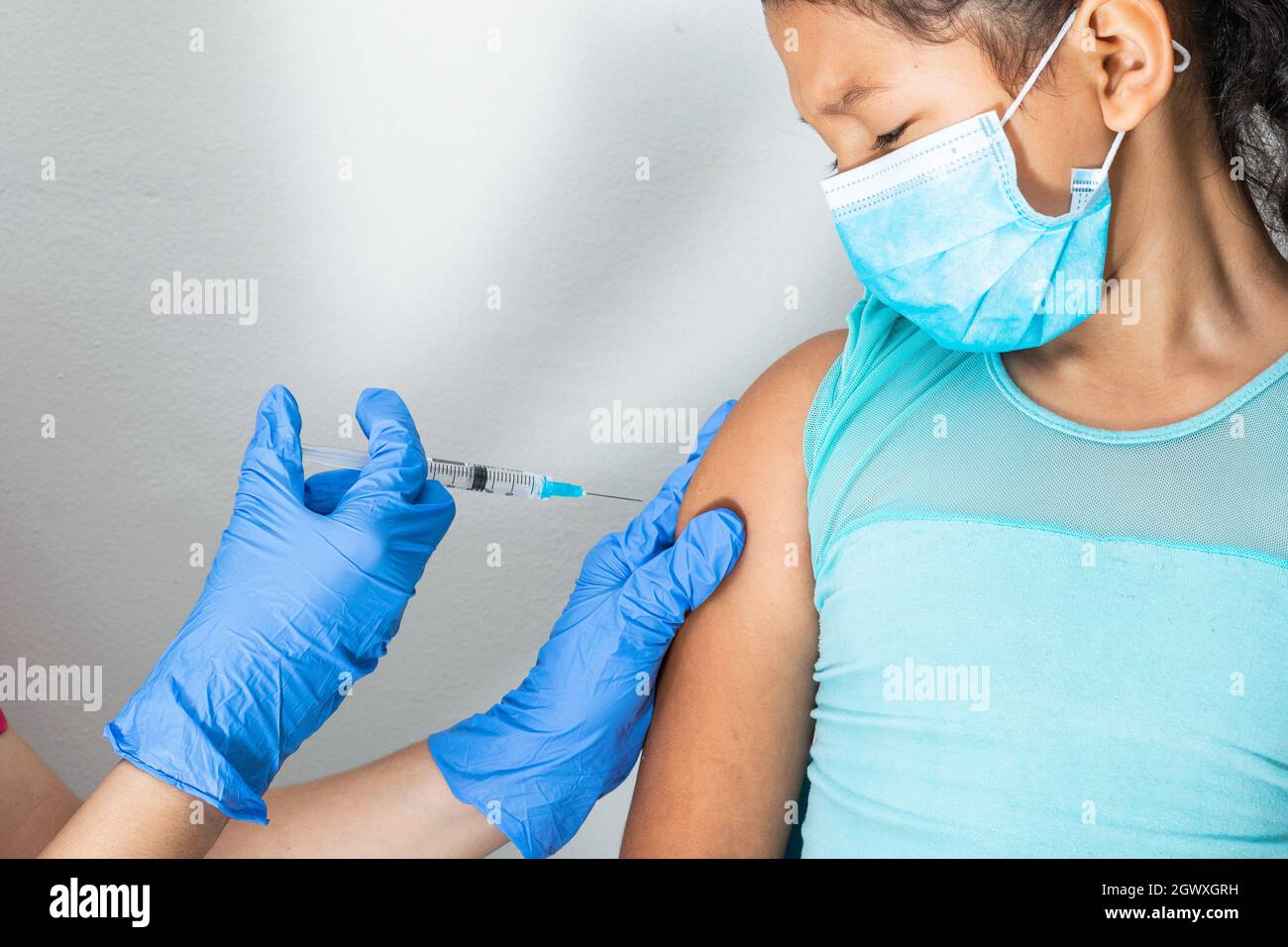 children's nurse administering injection in brown girl's arm. doctor ...