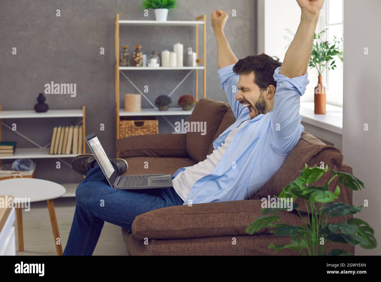 Sleepy tired young man stretching arms and yawning while working on ...