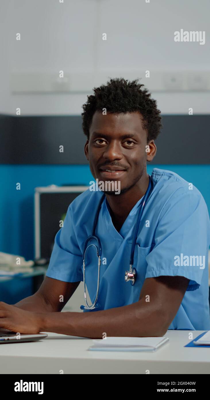 Portrait of male nurse with uniform and stethoscope using laptop on ...