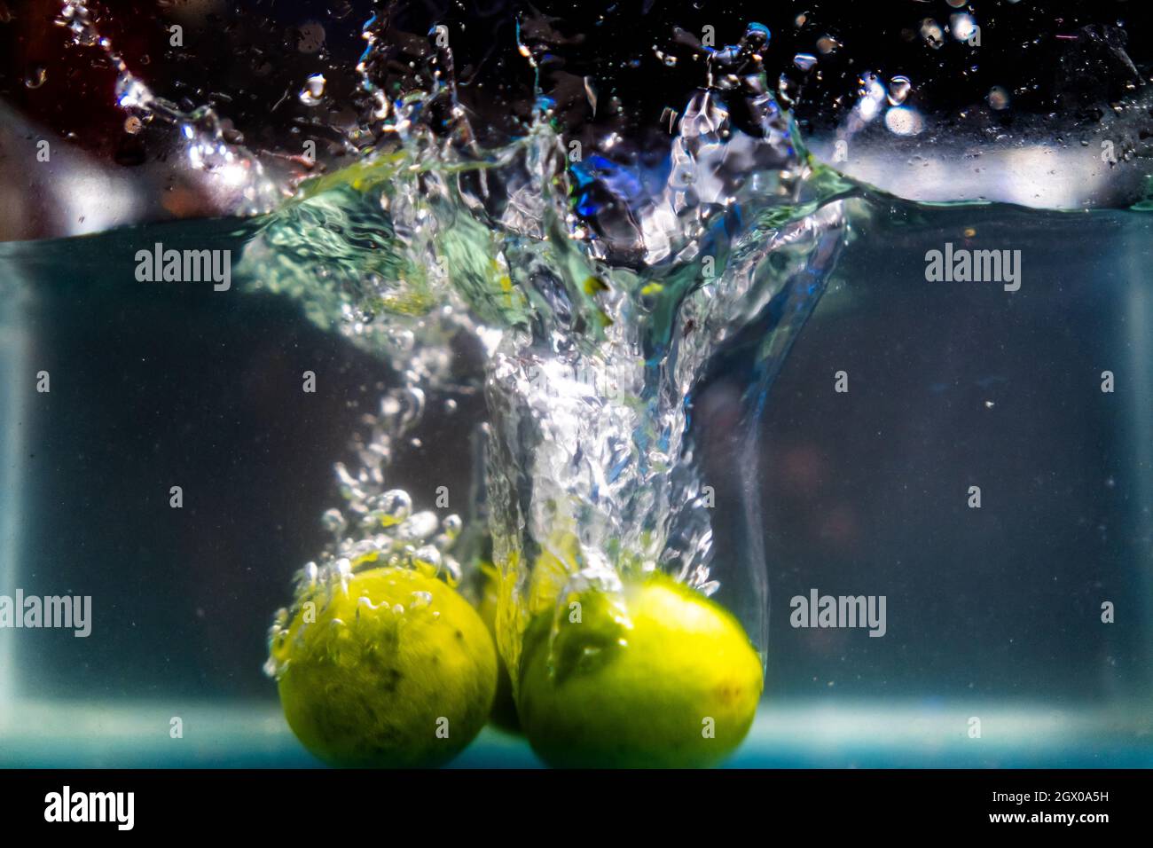 Three fresh limes falling deep in water with splash Stock Photo - Alamy