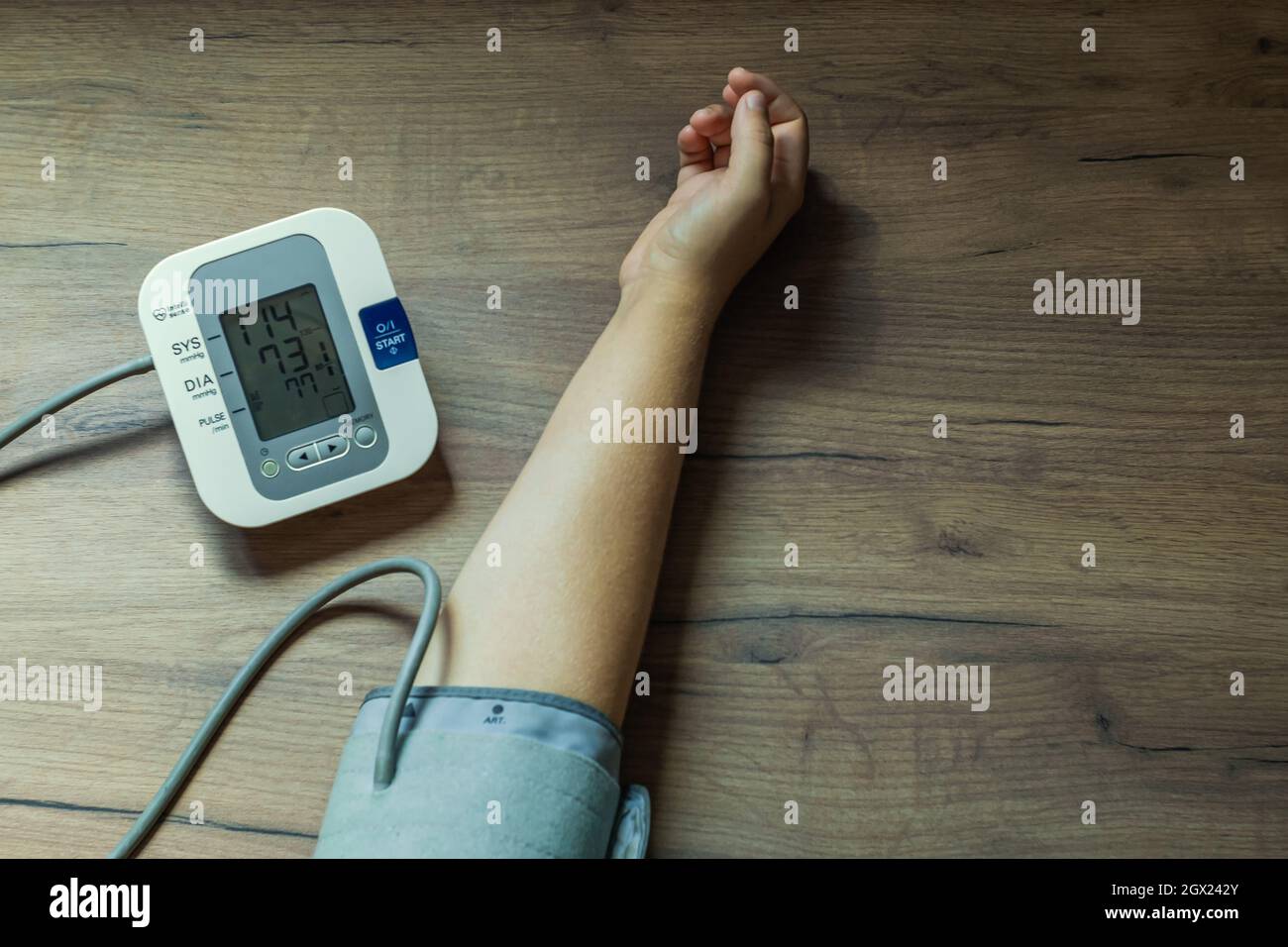 A woman's hand and an automatic tonometer on a wooden table. The screen ...