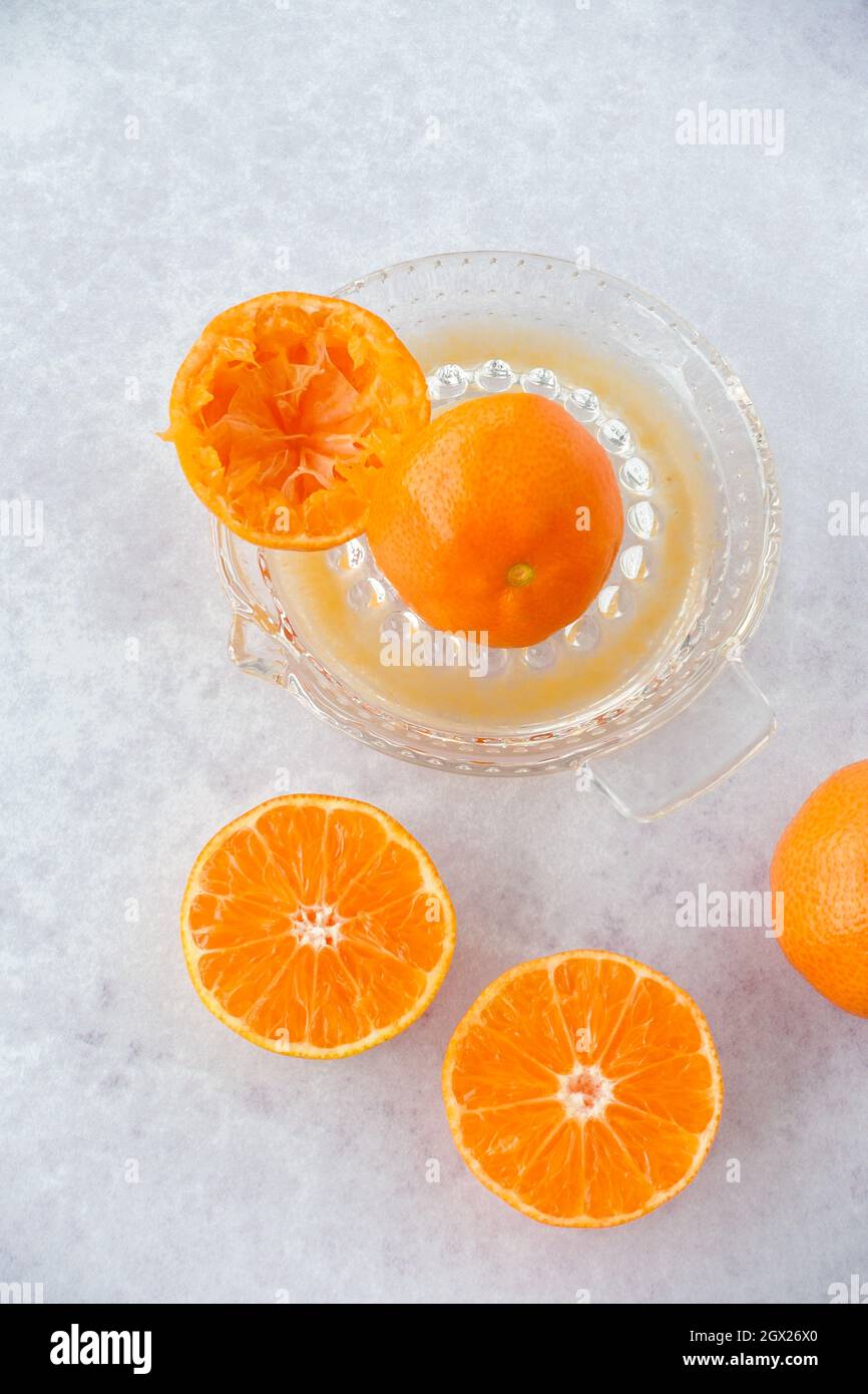 Clementines cut in halves on citrus juicer and gray patterned ...