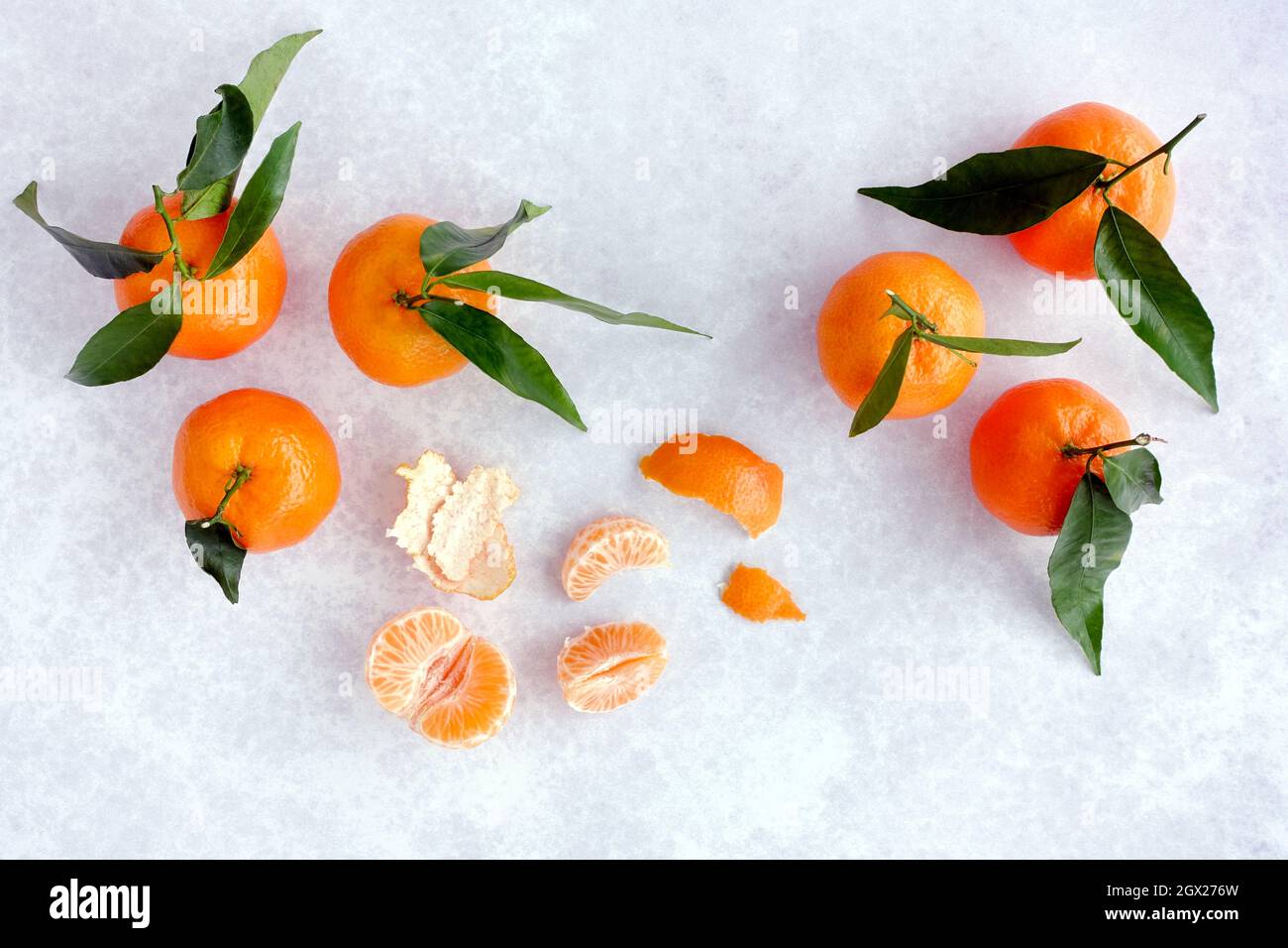 Top view of whole clementines with leaves, peel and segments on gray ...